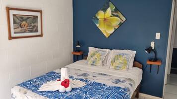 Quarto de hotel com uma cama, um quadro pendurado na parede e uma mesa de cabeceira com abajur.