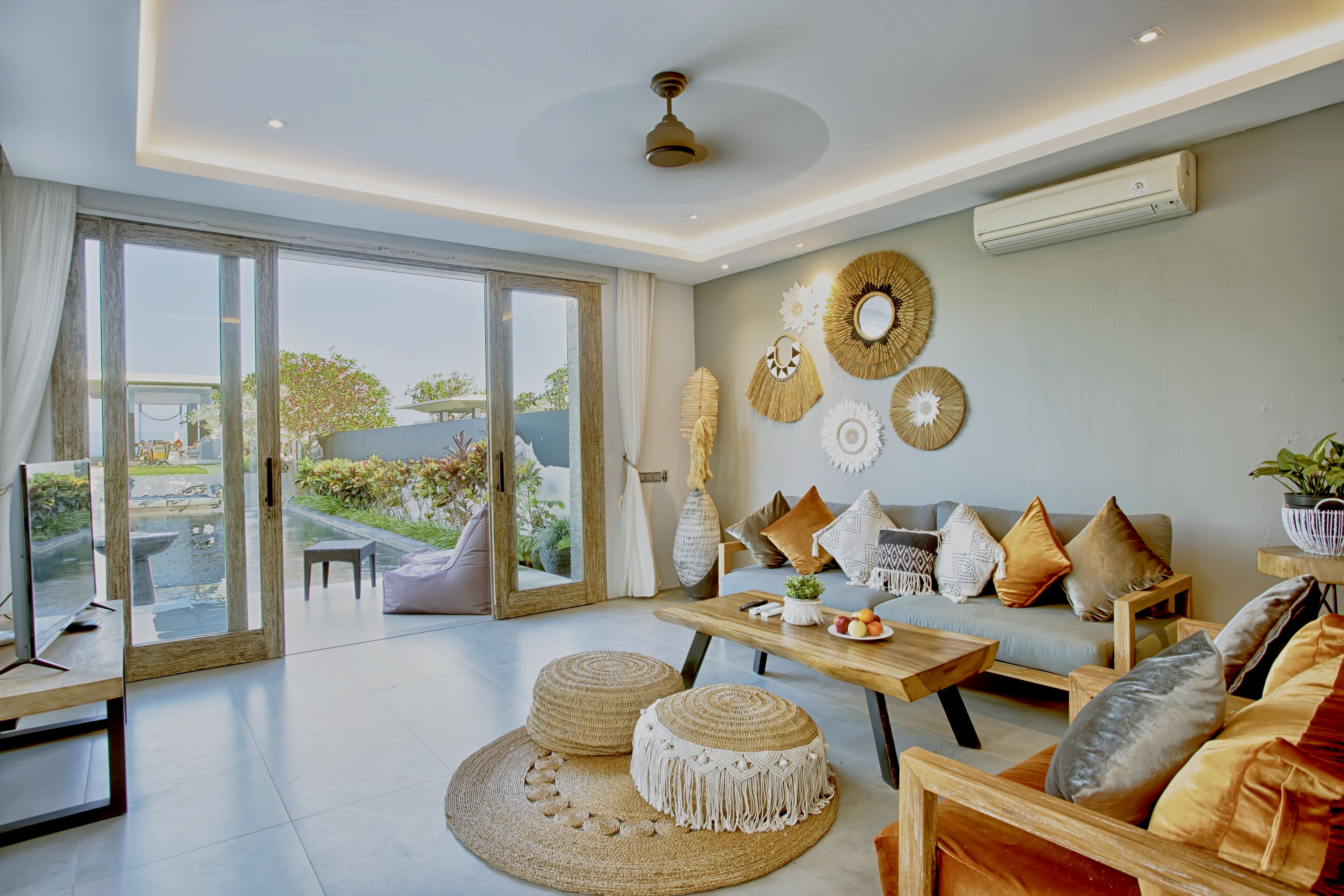 Sala de estar moderna com um sofá, uma mesa de centro e uma televisão. Há painéis decorativos na parede e uma janela grande com vista para o exterior.