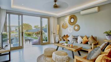 Sala de estar moderna com um sofá, uma mesa de centro e uma televisão. Há painéis decorativos na parede e uma janela grande com vista para o exterior.