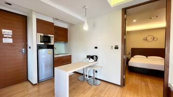 Quarto de hotel compacto com cozinha compacta, cama e pequena área de refeições.