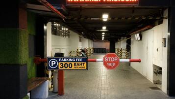 Entrada de estacionamento com placa de pare, aviso de taxa de estacionamento e sinal de website.