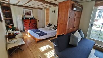 Quarto compacto com cama, sofá, escrivaninha e guarda-roupa.