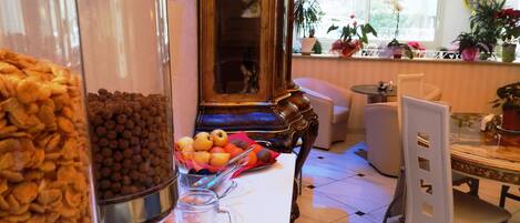 Espaço de buffet com cereais, frutas e um jarro de leite.