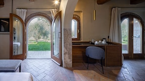 Uma cozinha acolhedora com um banco de madeira, uma mesa de jantar e vista para um jardim através de janelas em arco.