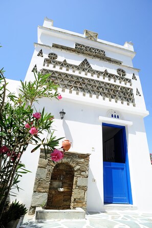 Um edifício branco com uma porta azul e um arco de pedra.