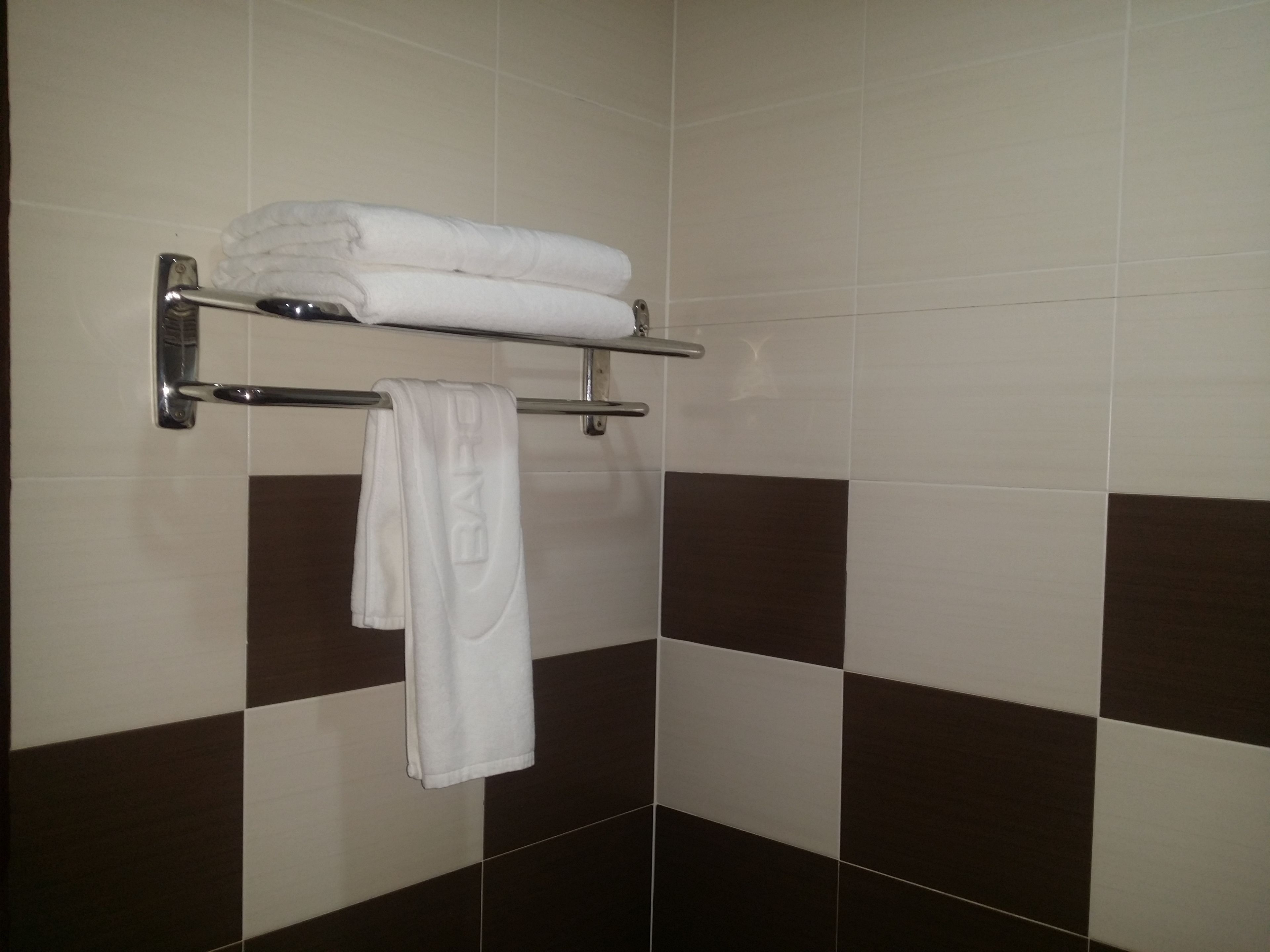 Casa de banho com porta-toalhas com toalhas dobradas e toalha pendurada.