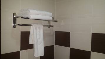 Casa de banho com porta-toalhas com toalhas dobradas e toalha pendurada.