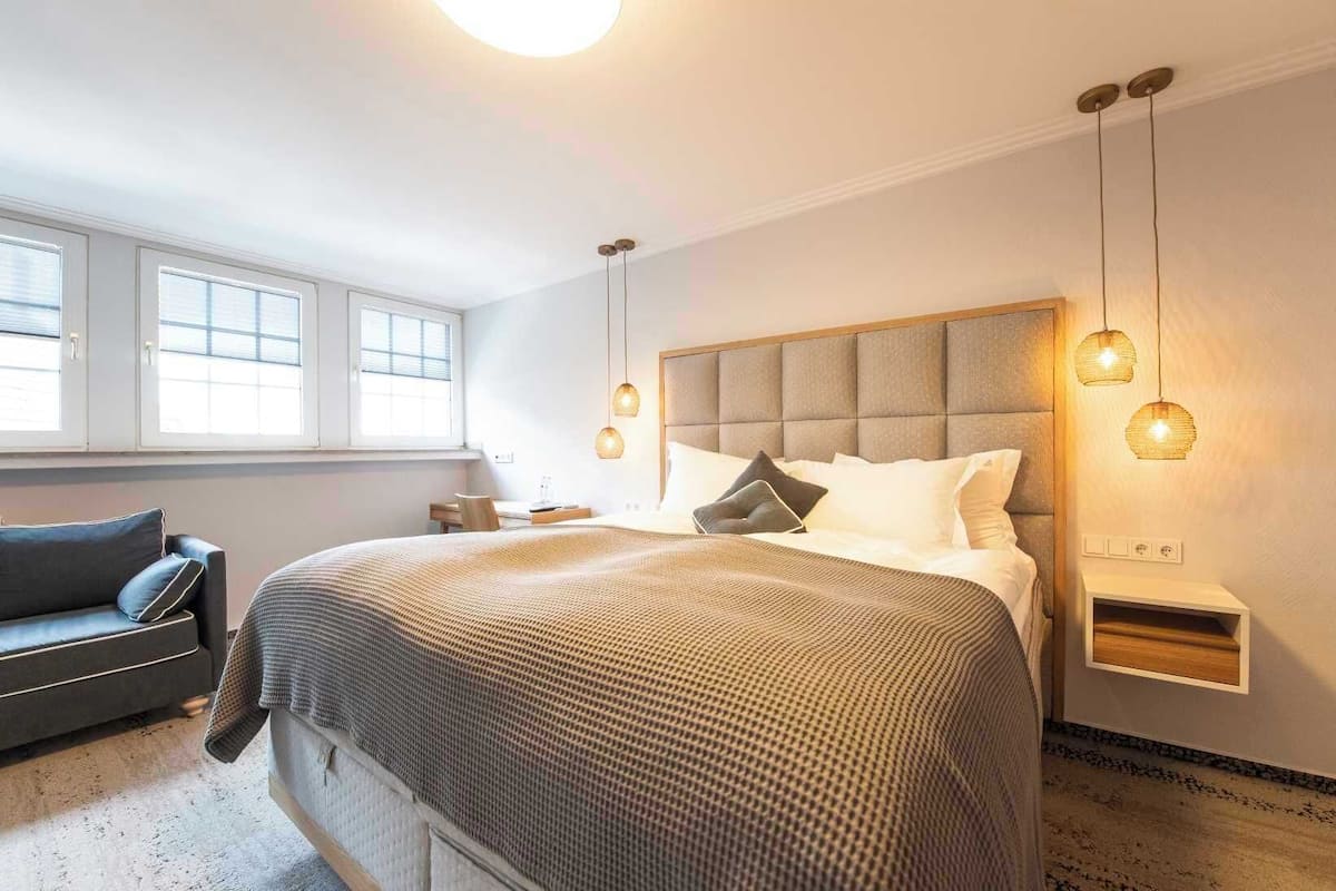 Quarto moderno com cama grande, mesas de cabeceira, escrivaninha e um sofá.