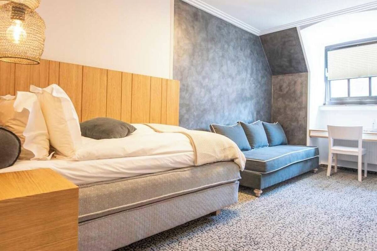 Um quarto com cama, sofá, escrivaninha e cadeira.