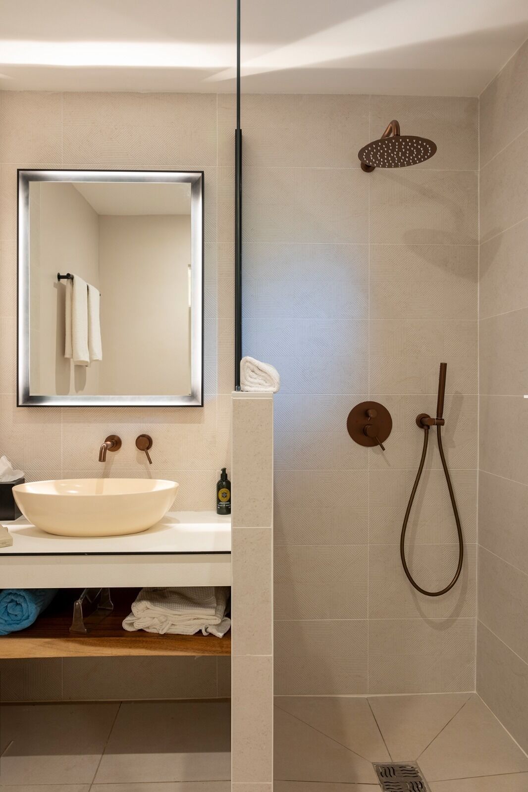 Casa de banho moderna com um espelho grande, uma pia, um chuveiro com chuveiro manual e um porta-toalhas.