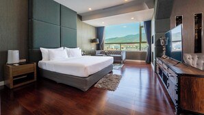 Quarto de hotel moderno com uma cama grande, mesa de cabeceira de madeira, televisão e vista para as montanhas.
