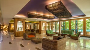 Um hall amplo com móveis de vime, grandes janelas e um teto com luminárias trançadas.