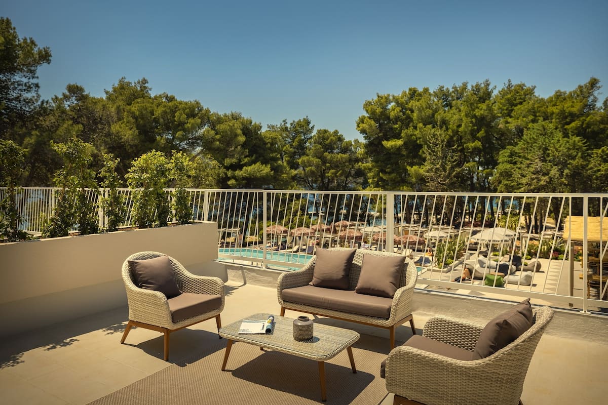 Varanda com móveis de vime, piscina e vista para árvores.