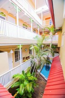 Um edifício com vários níveis, varandas, piscina e vegetação exuberante.