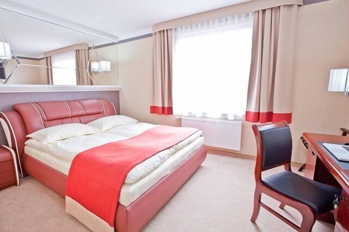 Quarto de hotel com uma cama, uma mesa e uma cadeira.