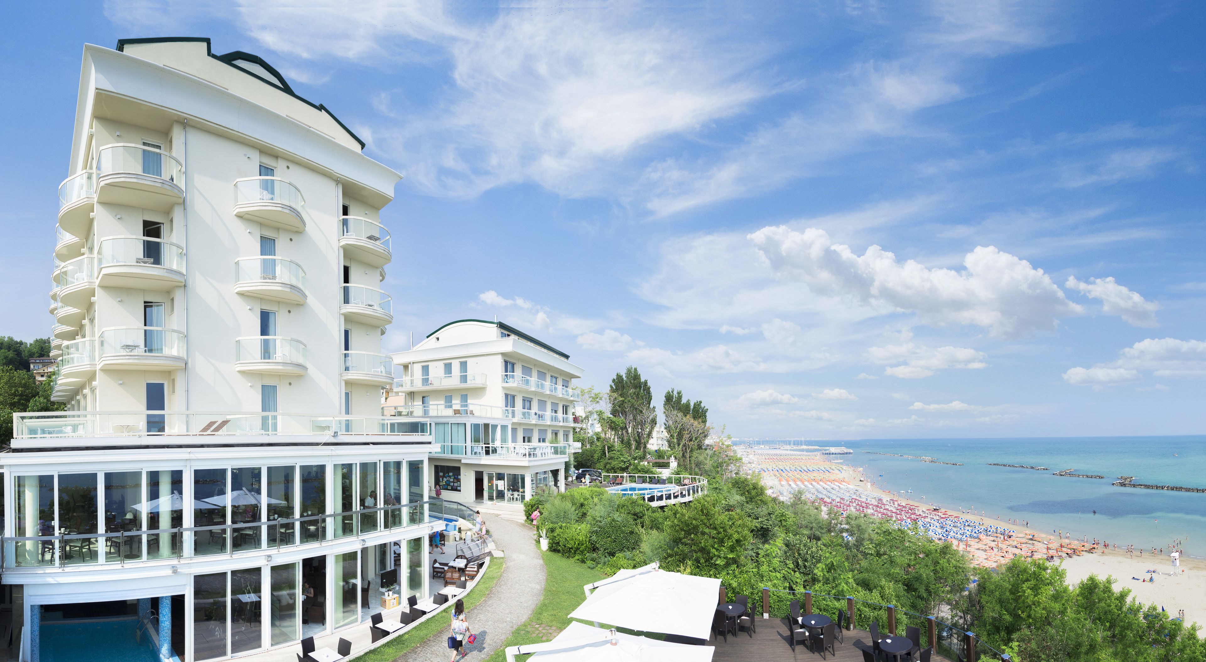 Um hotel moderno com várias varandas, piscina e vista para a praia.