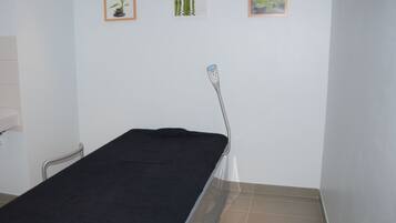 Um quarto com uma cama preta, uma cadeira e três quadros na parede.