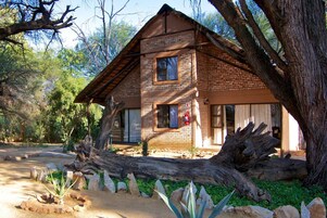 Uma casa de dois andares de tijolo com telhado inclinado, janelas amplas e um extintor de incêndio fixado na parede.
