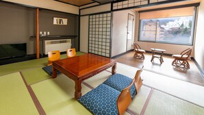 Um quarto japonês tradicional com tatames, uma mesa de madeira baixa e uma porta de correr.