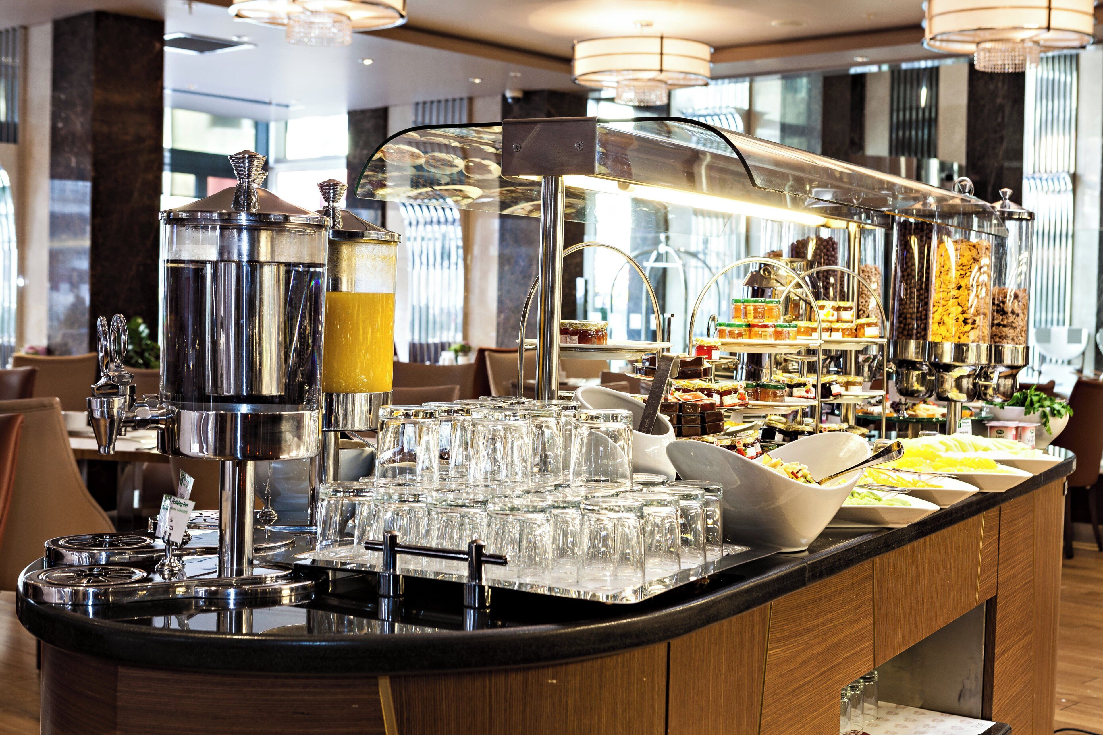 Disposição de buffet com diversos alimentos e um dispensador de bebidas.