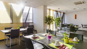 Uma sala de conferências com mesas, cadeiras e plantas em vasos.