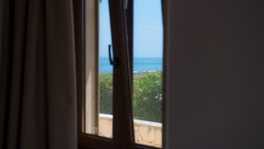 Uma janela com vista para o mar e vegetação.