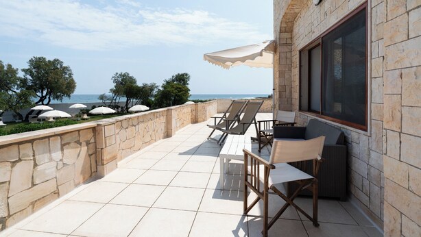 Um terraço com paredes de pedra, mobiliário de exterior e vista para o mar.