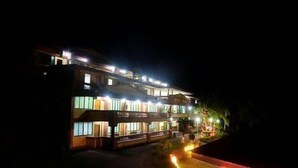 Um hotel com vários andares, janelas iluminadas e uma entrada bem iluminada.