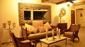 Uma sala de estar aconchegante com um sofá, duas poltronas, uma mesa de centro e um espelho decorativo.