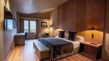 Quarto de hotel moderno com uma cama grande, uma escrivaninha, uma cadeira e vista para o exterior.