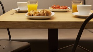 Paredes revestidas de madeira, uma mesa com itens de café da manhã e um quadro.