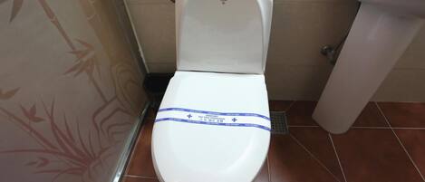 Sanitário branco com faixa azul e dispensador de álcool em gel na parede.