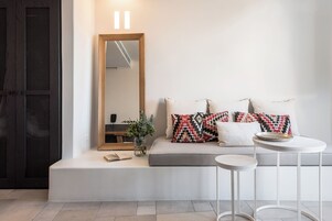 Uma sala de estar moderna com um sofá, uma mesa redonda e um espelho.