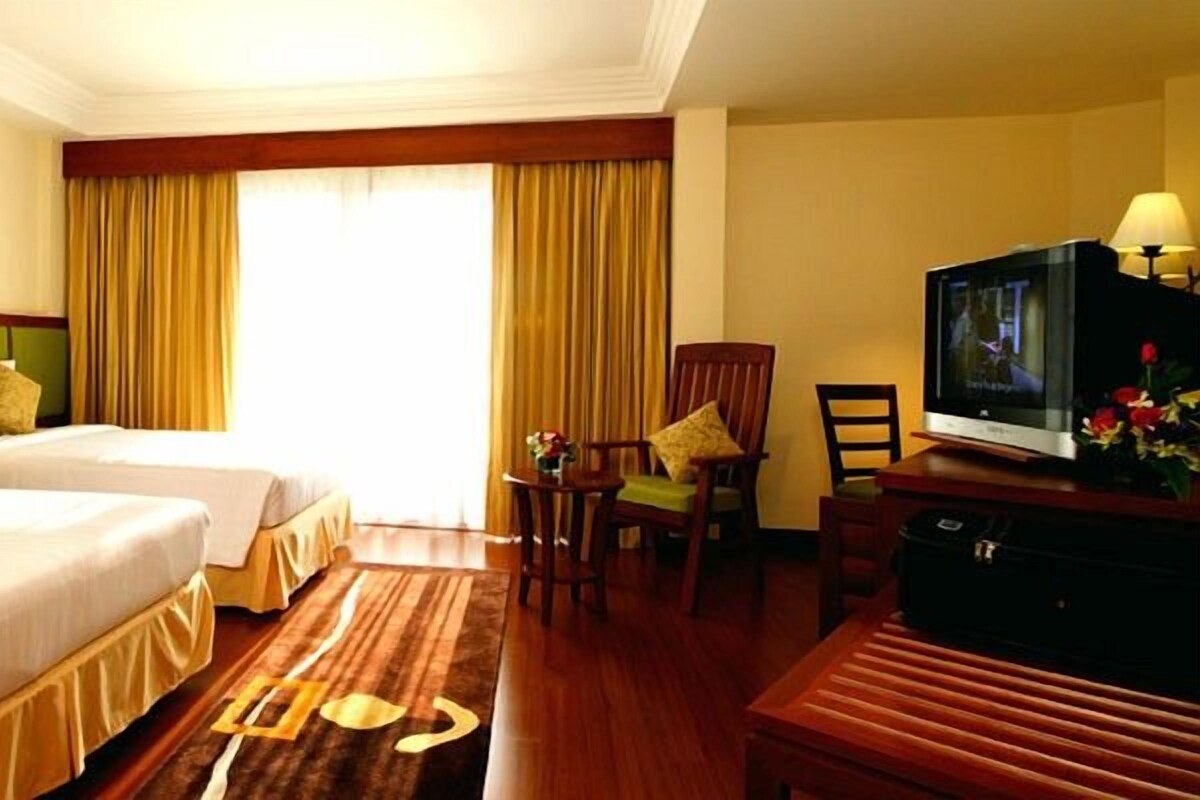 Quarto de hotel com duas camas, televisão, escrivaninha e uma cadeira.