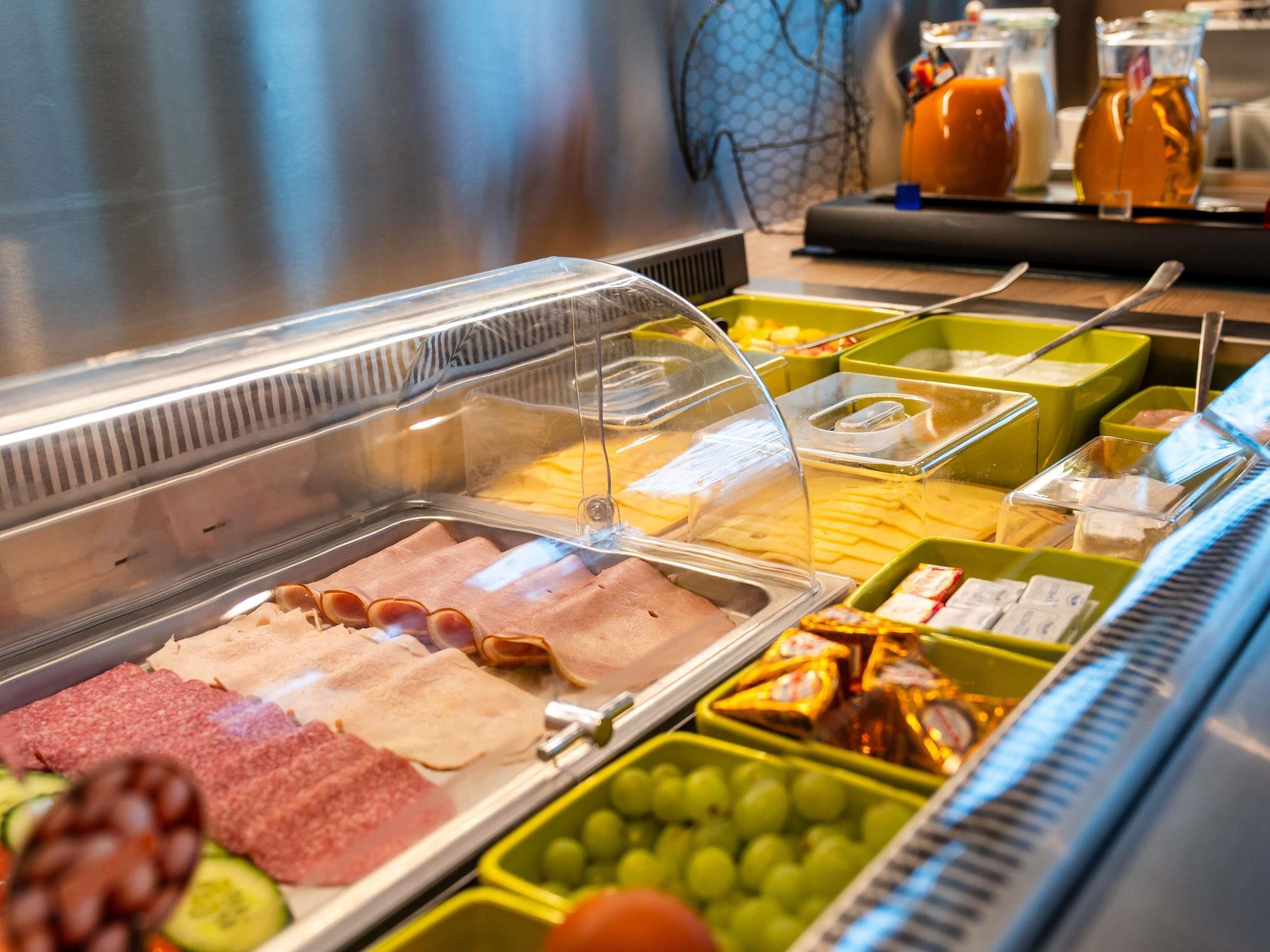 Buffet com diversas opções de comida, incluindo carnes, queijos e frutas.