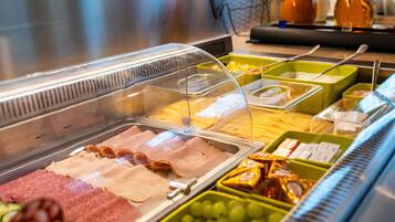 Buffet com diversas opções de comida, incluindo carnes, queijos e frutas.