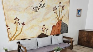 Sala de estar com sofá de madeira, mesa de centro e uma pintura na parede.