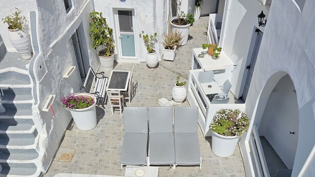 Área de piscina no terraço, piscina azul cristalina, espreguiçadeiras e plantas em vasos.