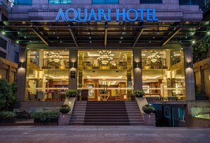 Exterior do Aquari Hotel com uma entrada imponente, uma escadaria que leva ao saguão e uma fachada bem iluminada.