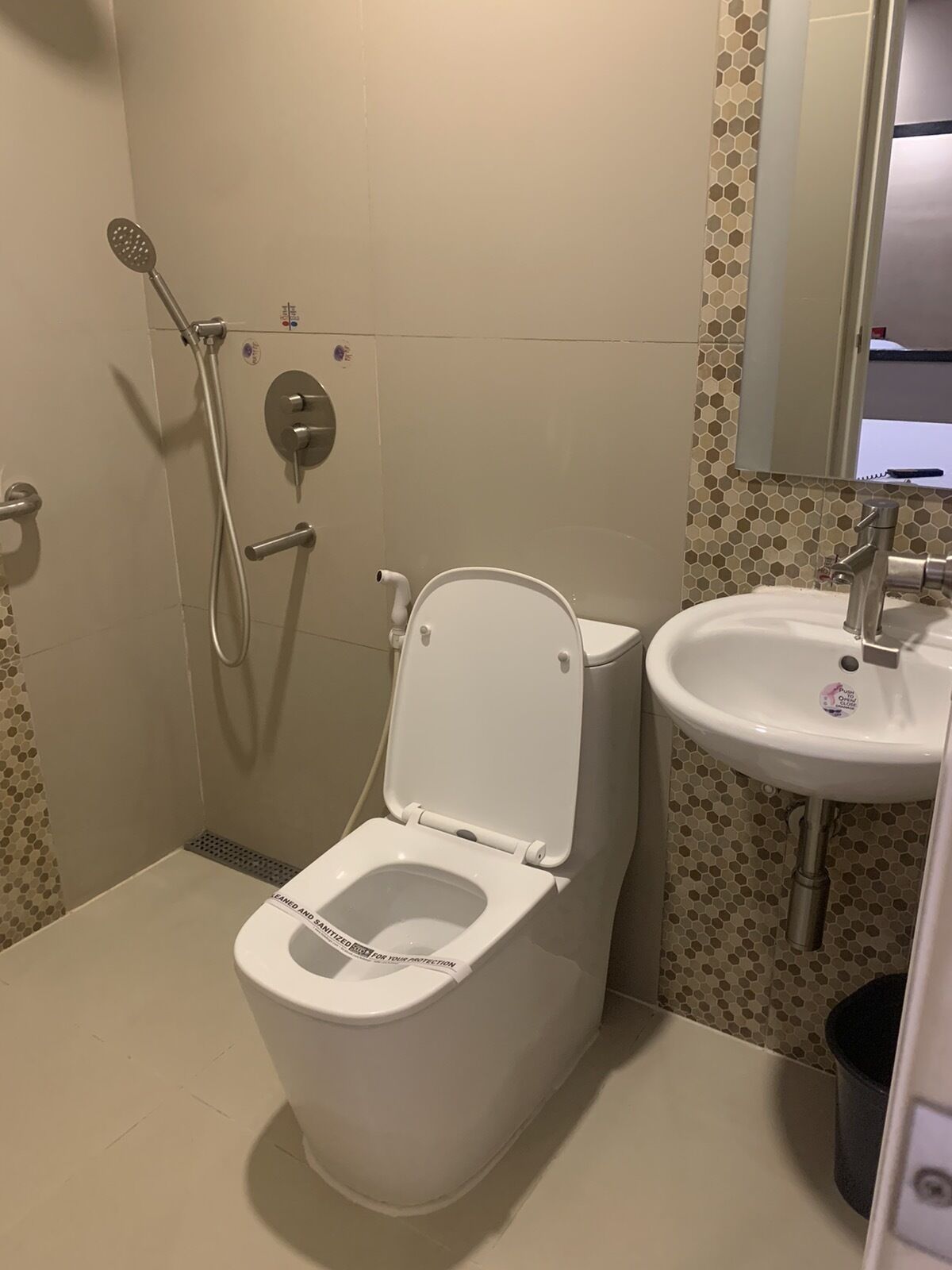Casa de banho com sanita, chuveiro e lavatório.