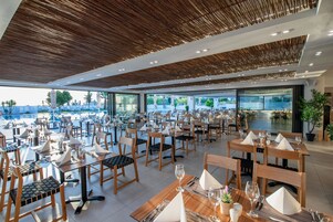 Um restaurante com mesas e cadeiras de madeira, janelas amplas e vista para a cidade.