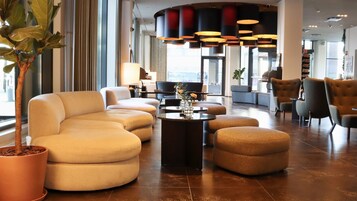Um lobby moderno de hotel com um sofá curvo, uma mesa de centro e um vaso de planta.