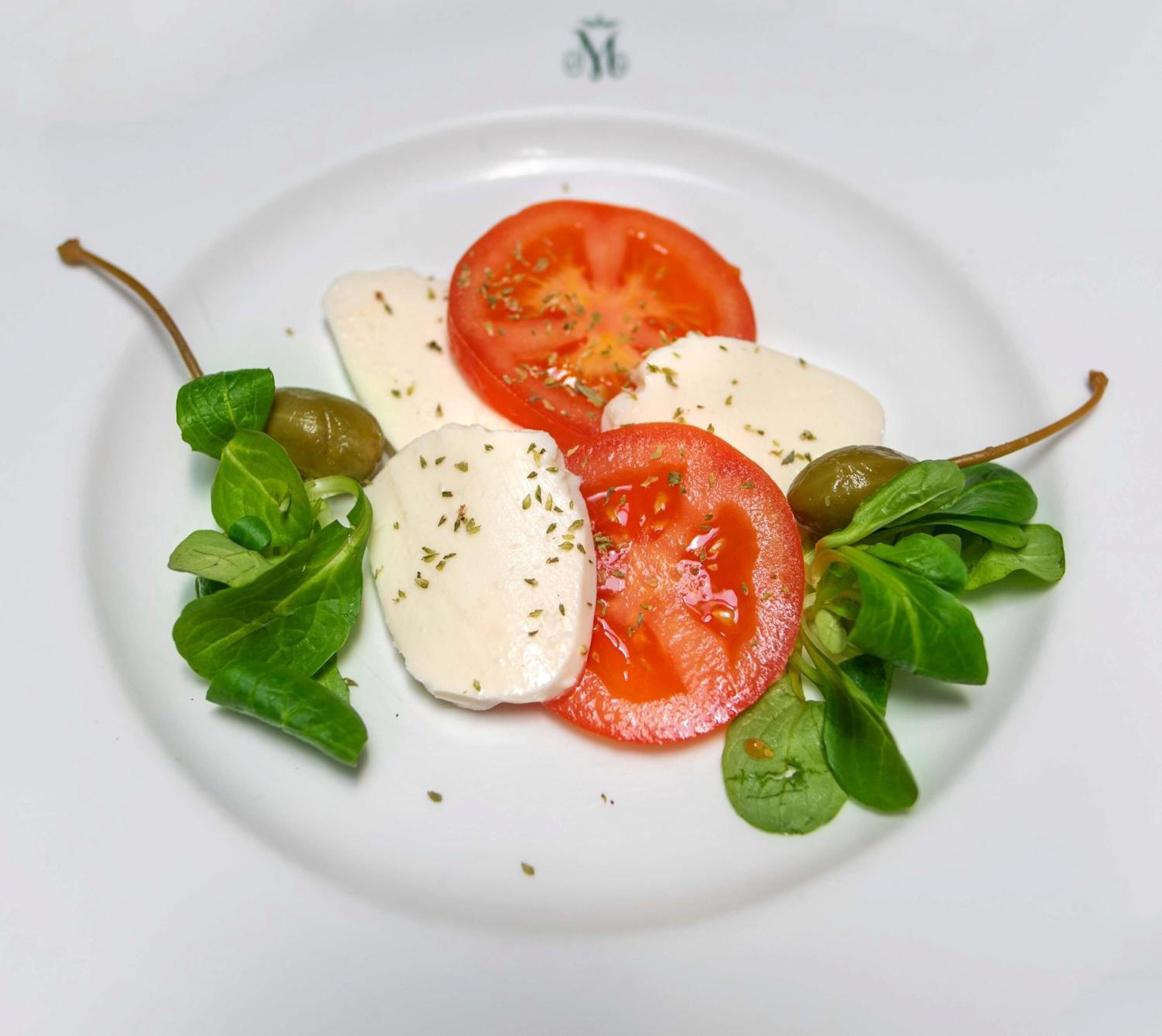 Uma salada Caprese com tomates, mussarela e folhas de manjericão.