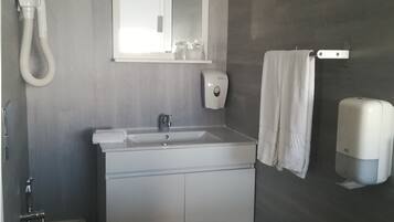 Casa de banho moderna com sanita, lavatório e espelho. Inclui secadores de mãos e dispensador de sabonete.