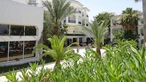 Um hotel moderno com vários edifícios brancos, área de piscina e vegetação exuberante.