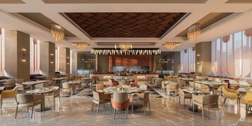 Uma ampla área de jantar com várias mesas e cadeiras, um bar central e um design de teto moderno.