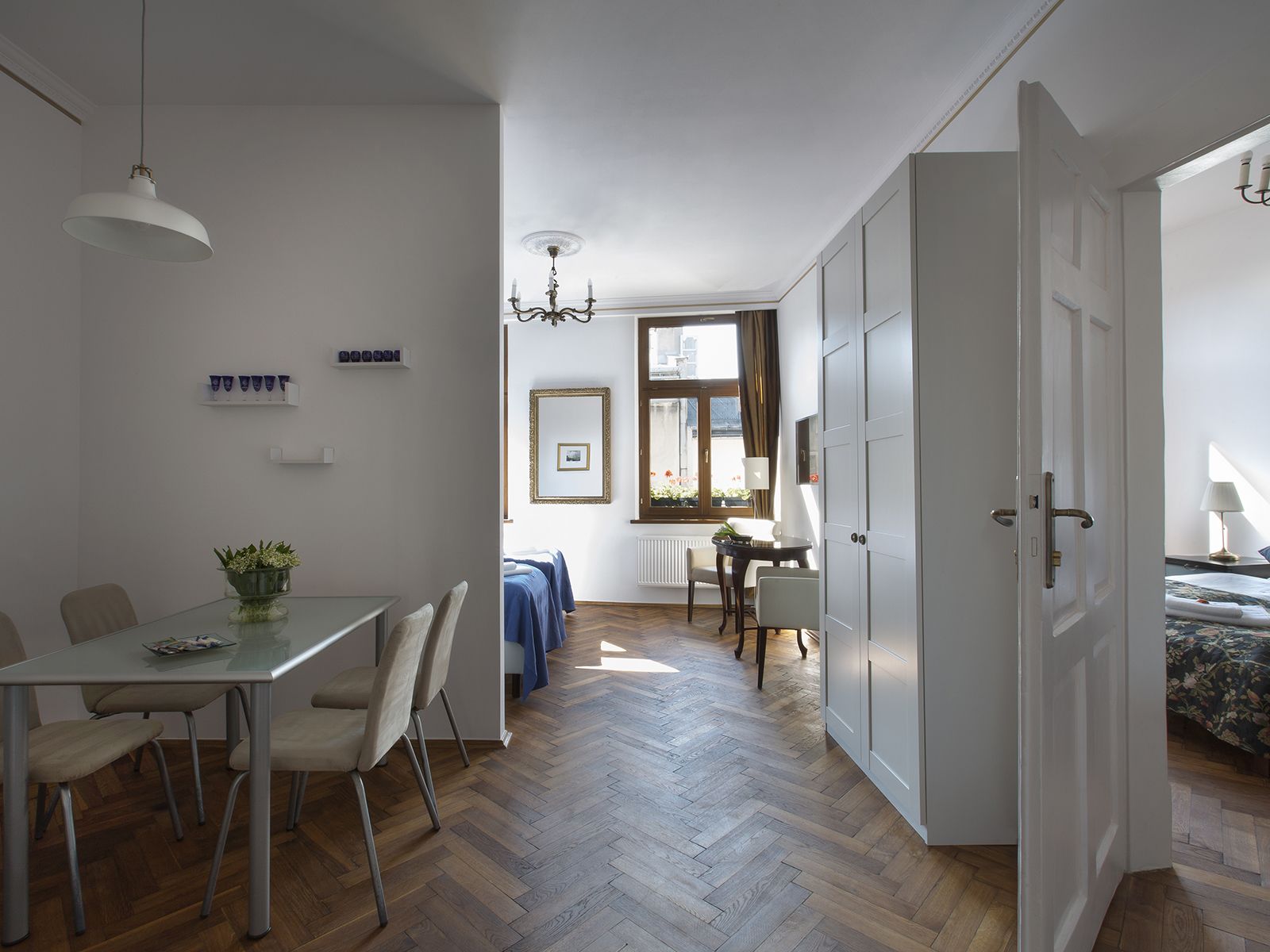 Quarto moderno com mesa de jantar, cadeiras, lustre, cama e guarda-roupa.