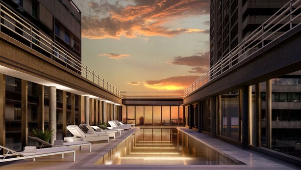 Uma área de piscina interna moderna, com espreguiçadeiras e vista para o pôr do sol.