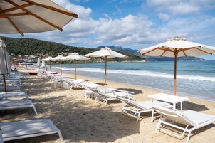 Na praia, areia branca, espreguiçadeiras, guarda-sóis