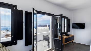 Quarto moderno com porta de vidro deslizante que dá para uma varanda com churrasqueira e mobiliário. Uma televisão de tela plana está fixada na parede.